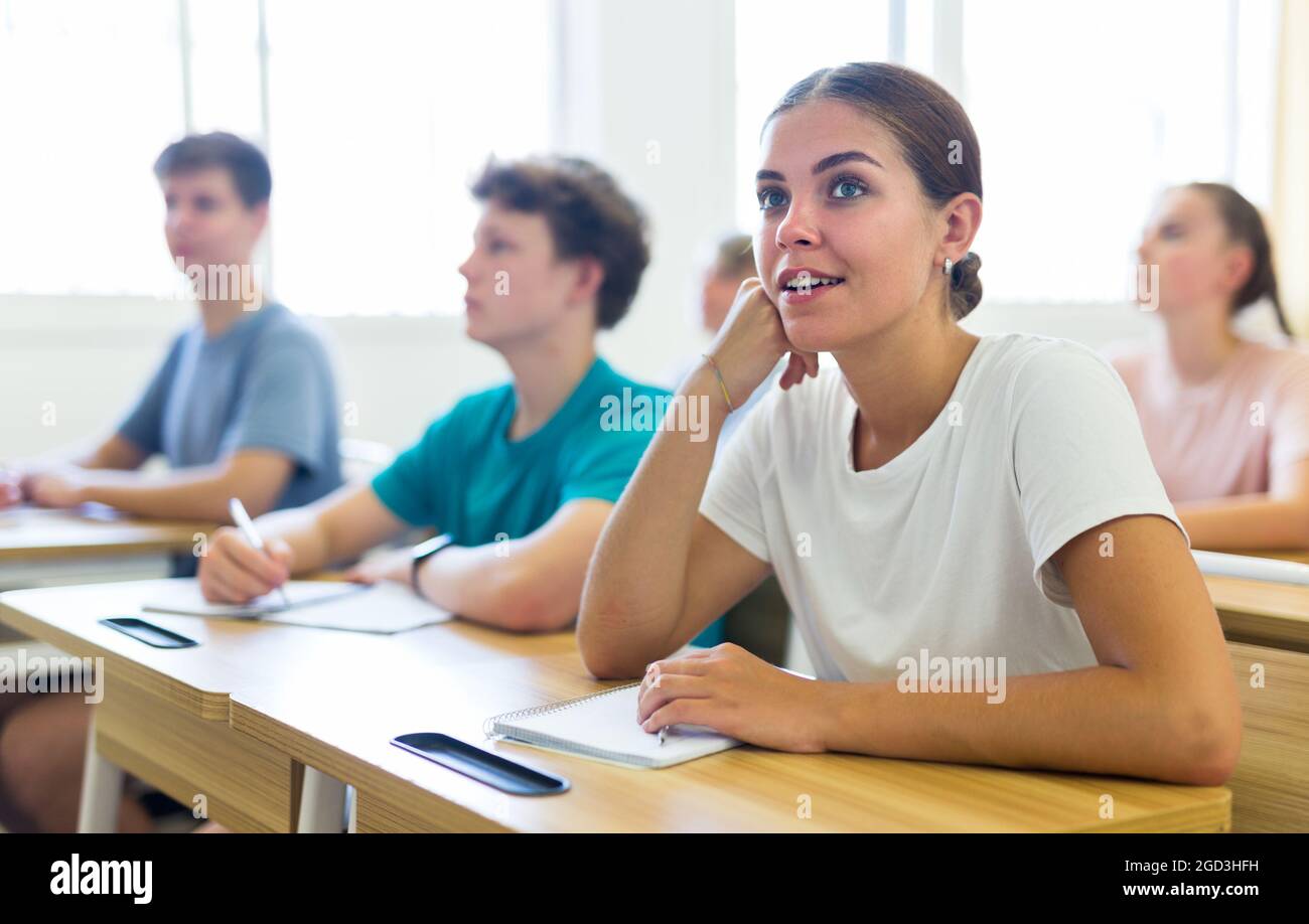 Smiling girl high school student listening to teacher during lesson ...
