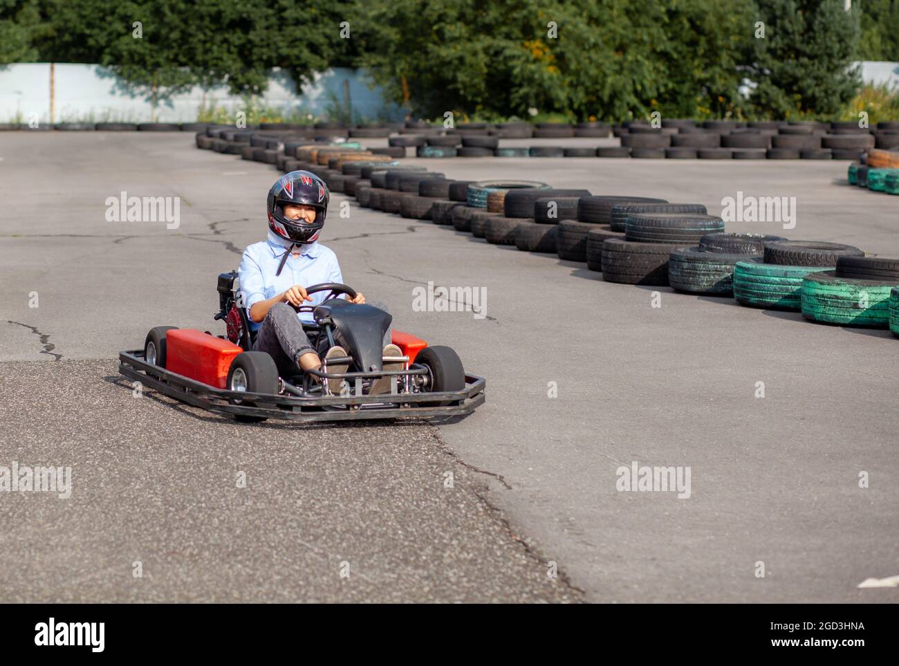 A girl or a woman in a hard hat rides a go-kart on a special track ...