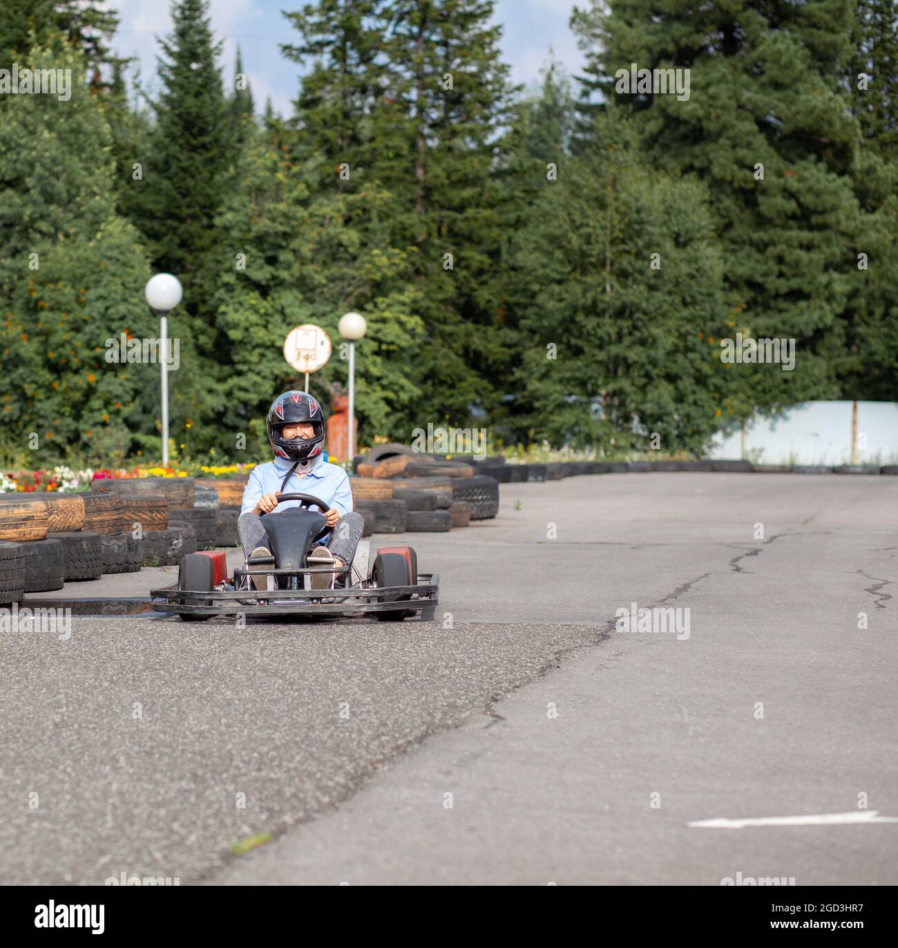 A girl or a woman in a hard hat rides a go-kart on a special track ...