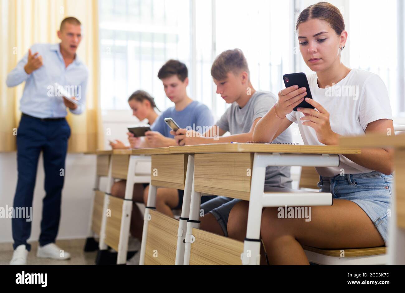 Teen pupils using mobile phones during lesson Stock Photo - Alamy