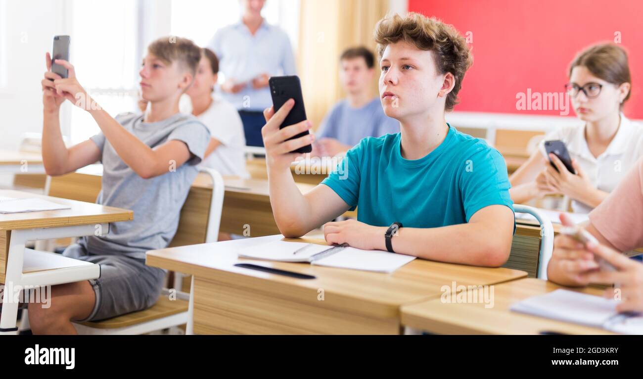 Teen student using smartphone while studying in college Stock Photo - Alamy