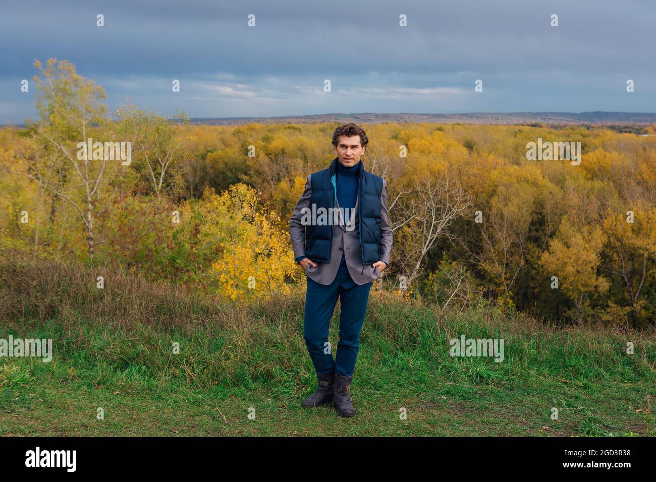 Tall handsome man walking outdoor in yellow autumn forest on the hill ...