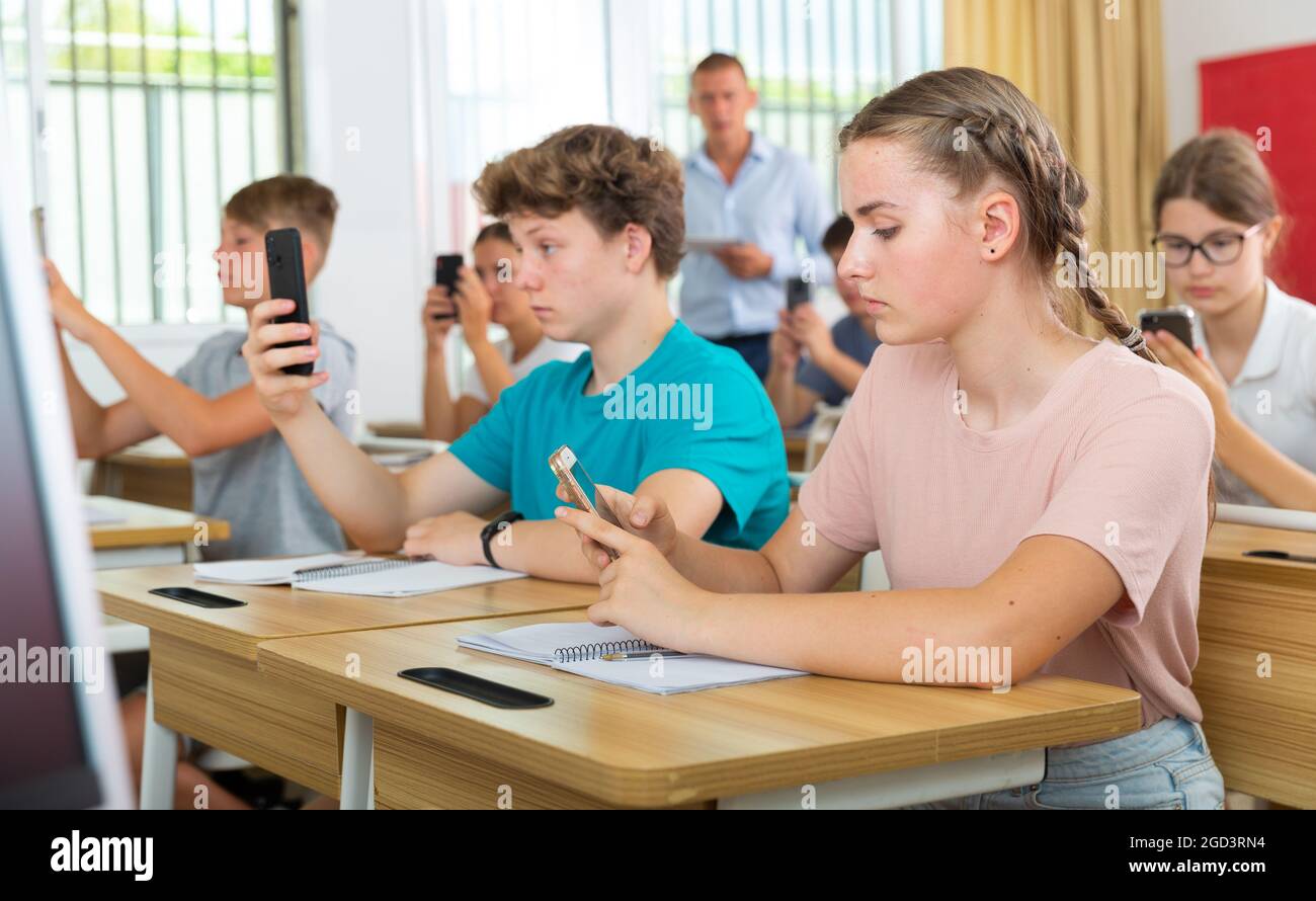 Group of modern teenagers sitting with mobile phones on lesson Stock ...