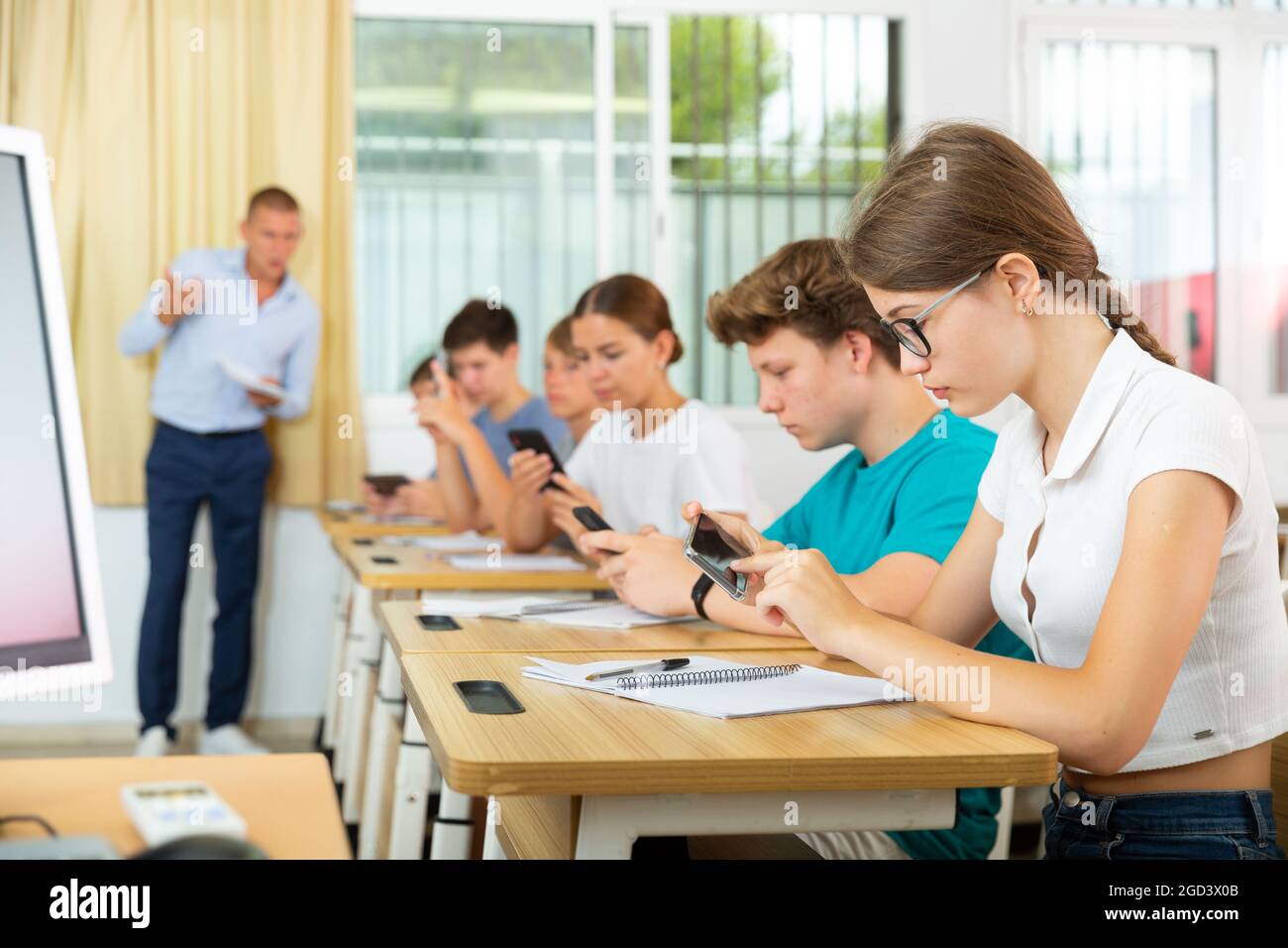 Group of modern teenagers sitting with mobile phones on lesson Stock ...