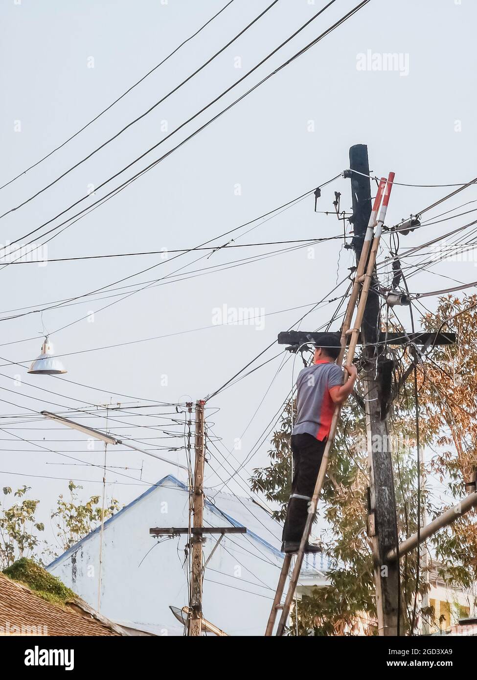 Asian electrician on a ladder repairing wire of the power line on ...