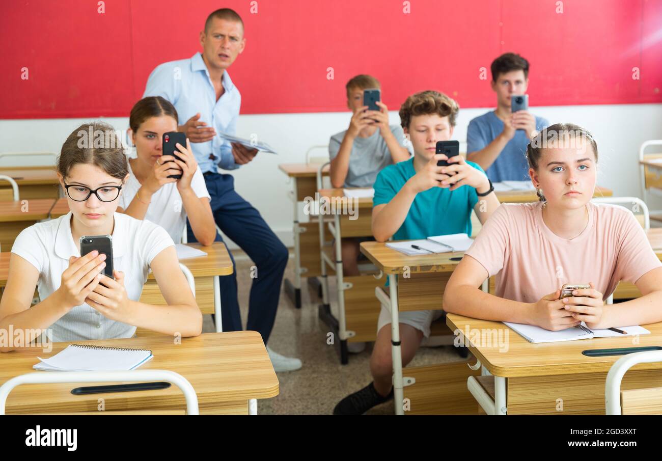 Teen pupils using mobile phones during lesson Stock Photo - Alamy