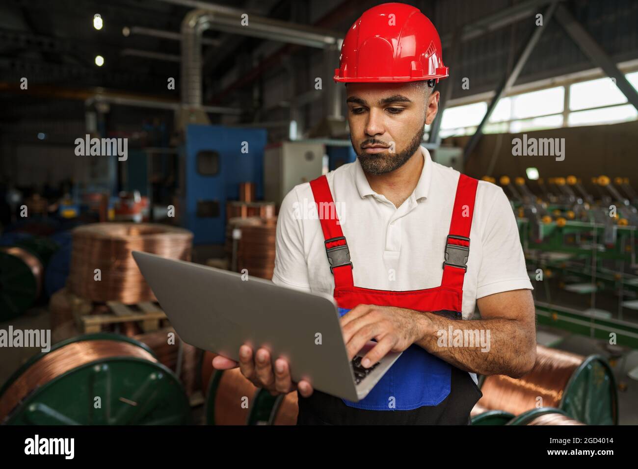 Industrial worker with laptop working in a cable production plant Stock ...