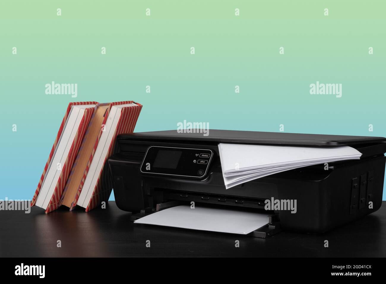 Home laser printer on desk against green background Stock Photo - Alamy