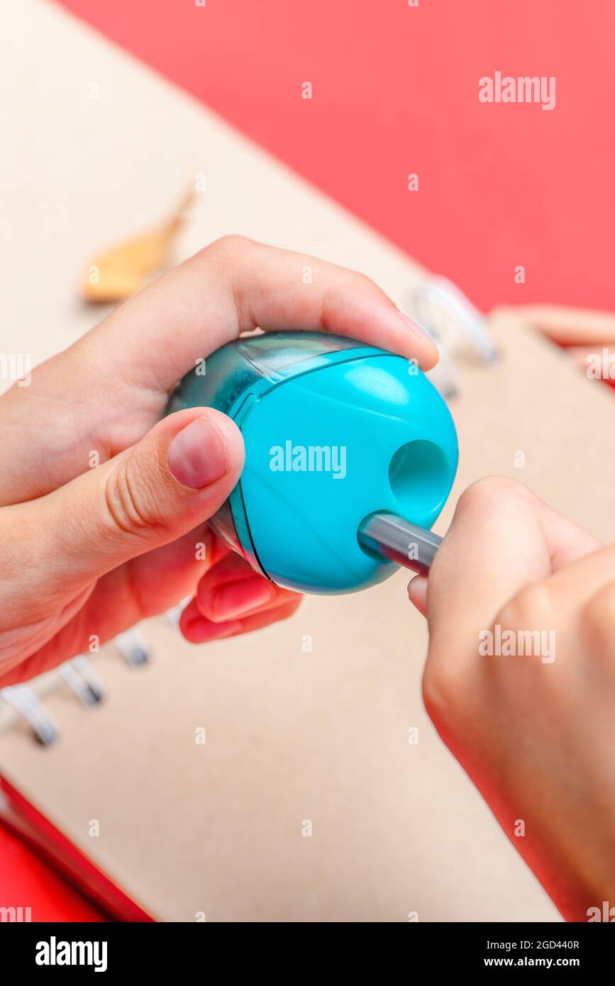 Sharpen pencils. The child's hands sharpen a pencil at school in the lesson. In the background ...
