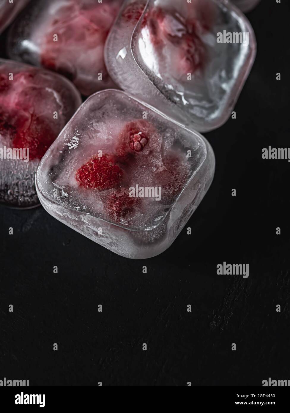 Raspberry frozen in the ice cube on black background. Fresh healthy ...