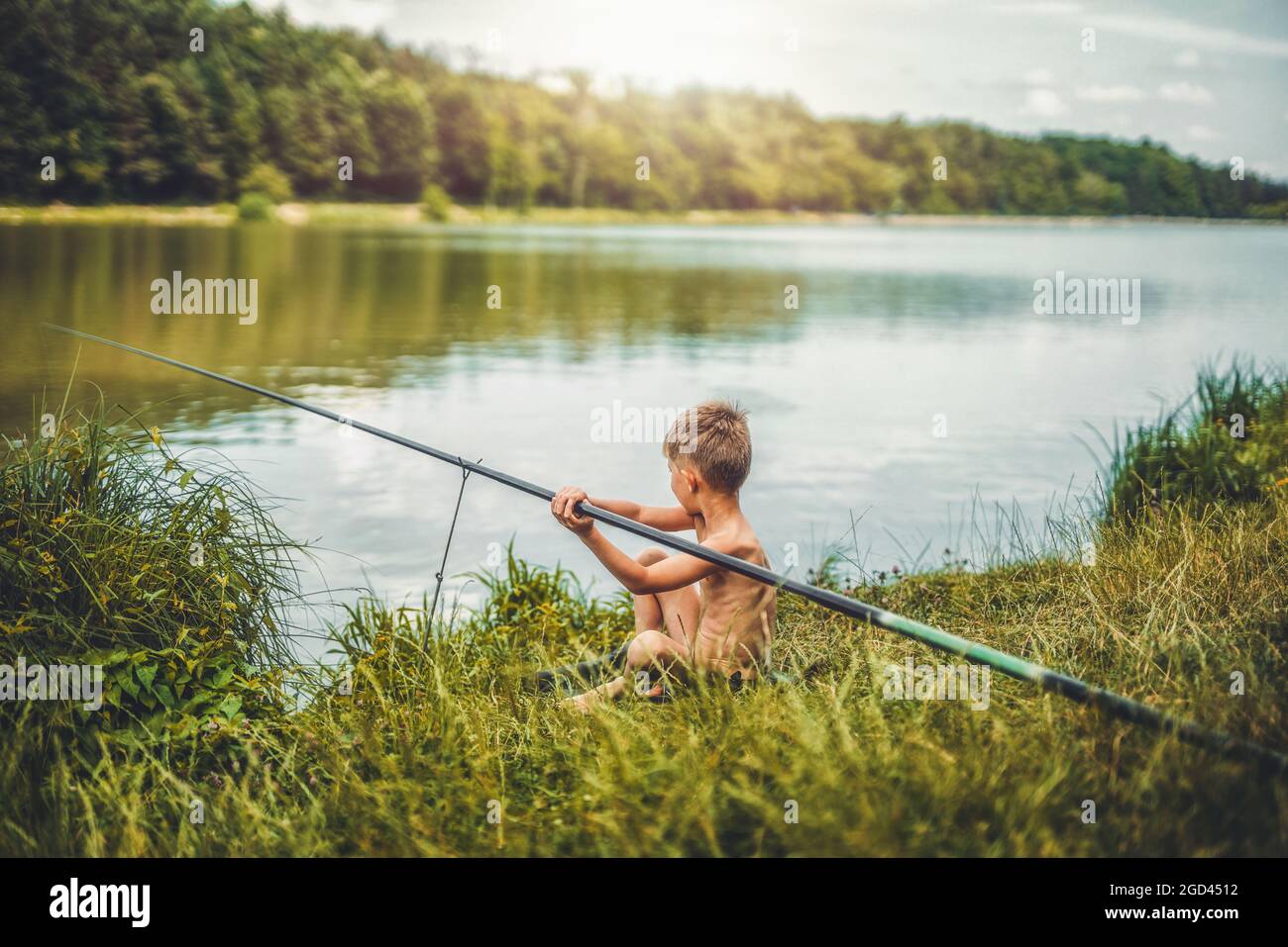 small child by the river and hunting fishes on a summer evening Stock ...