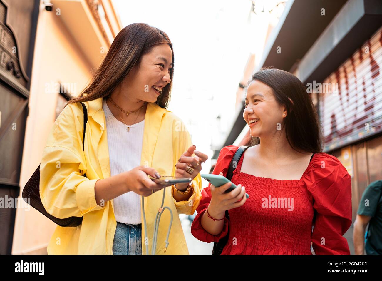 Young and pretty asian female friends talking and using their phones in ...
