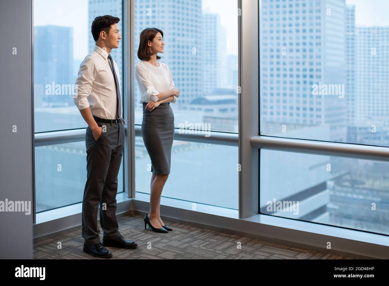 Confident business people looking through window Stock Photo - Alamy