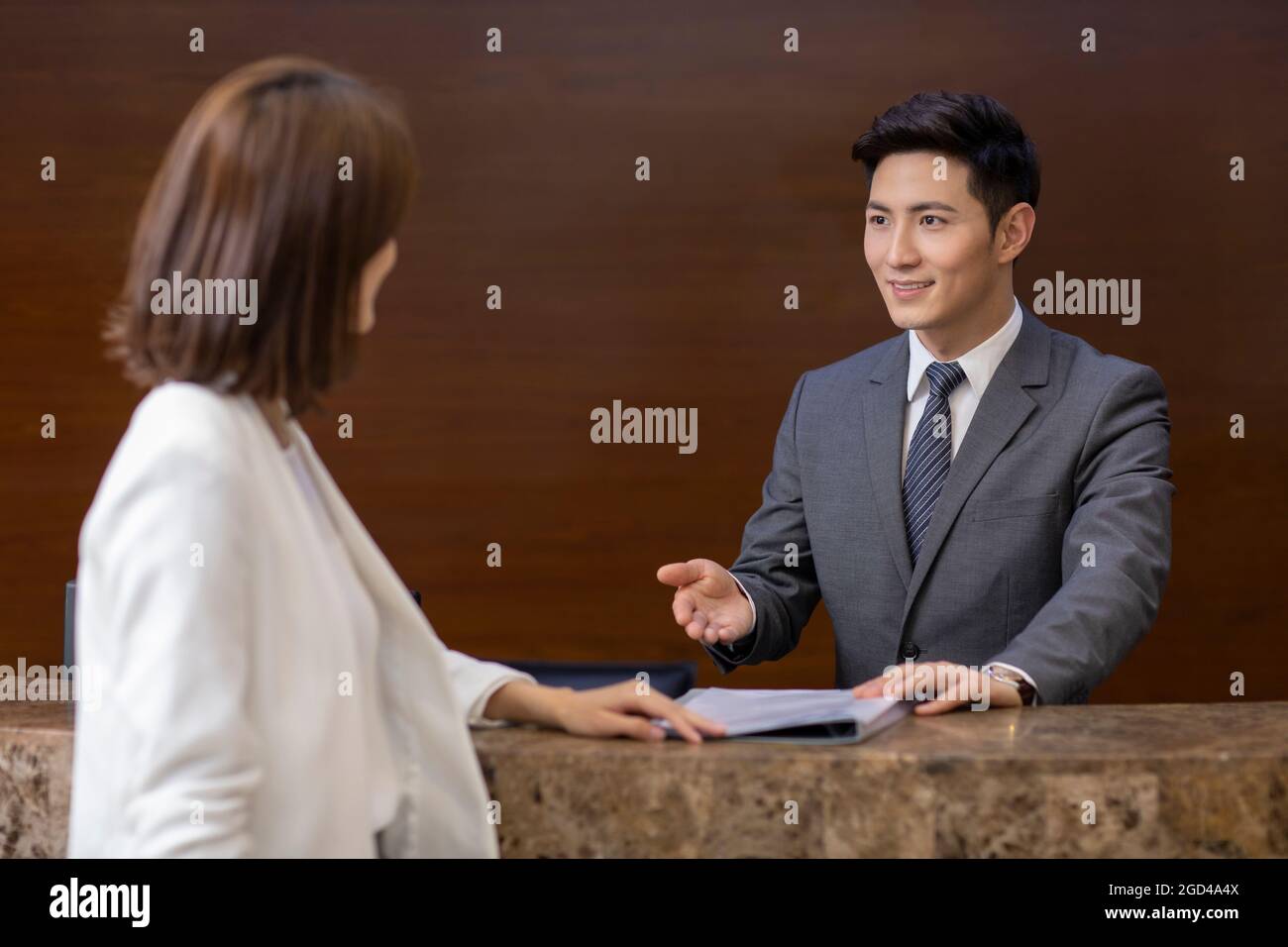 Hotel receptionist talking with customer Stock Photo - Alamy