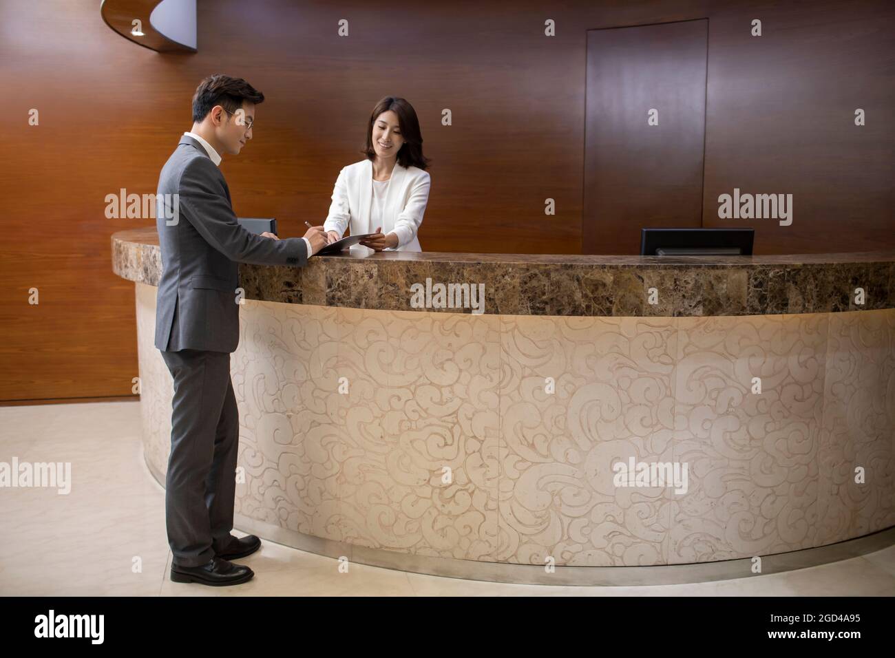Businessman checking in at front desk Stock Photo - Alamy