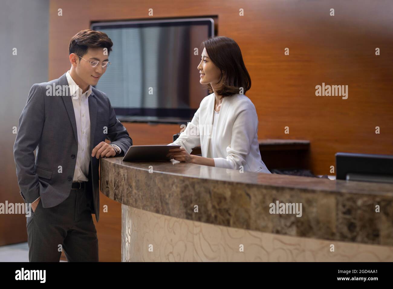 Hotel receptionist talking with customer Stock Photo - Alamy
