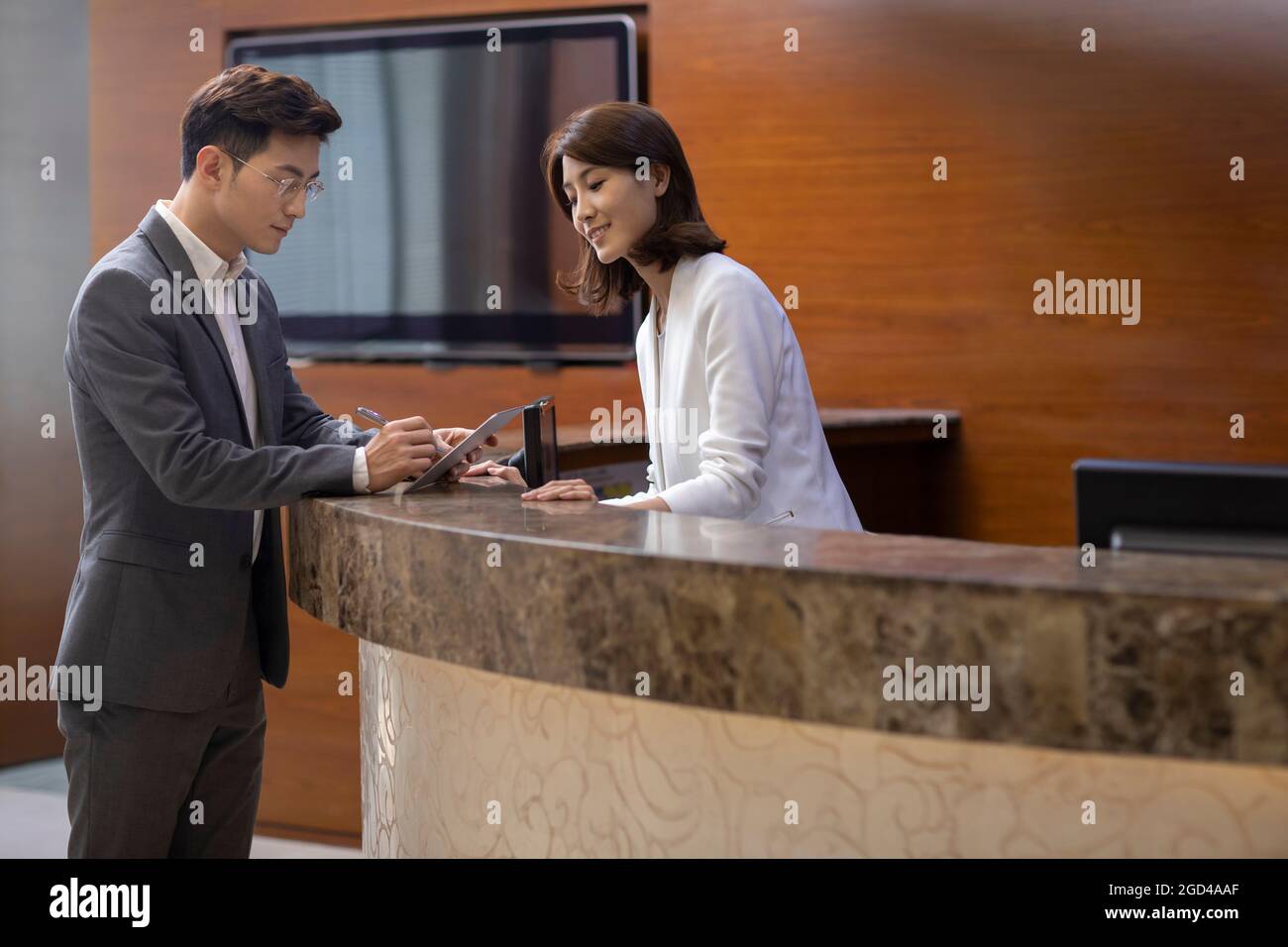 Businessman checking in at front desk Stock Photo - Alamy