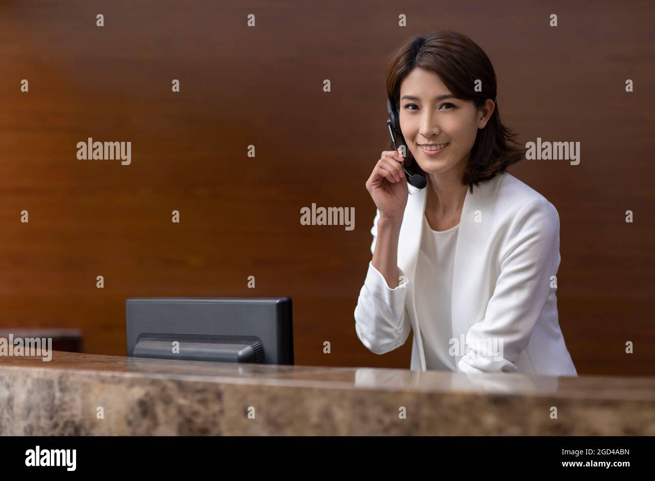 Hotel receptionist working with headset Stock Photo - Alamy
