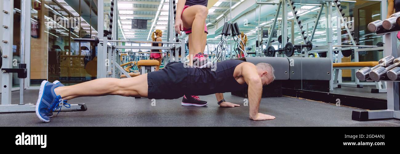 Woman coach training a man with hard push ups Stock Photo - Alamy