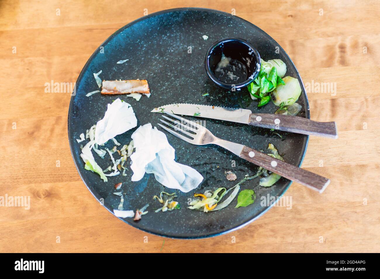 Empty dark plate left after dinner.Dirty dish after eaten with knife ...