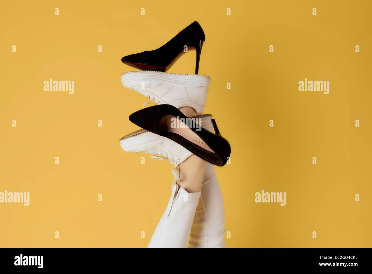 womens black shoes on inverted legs yellow background Stock Photo - Alamy