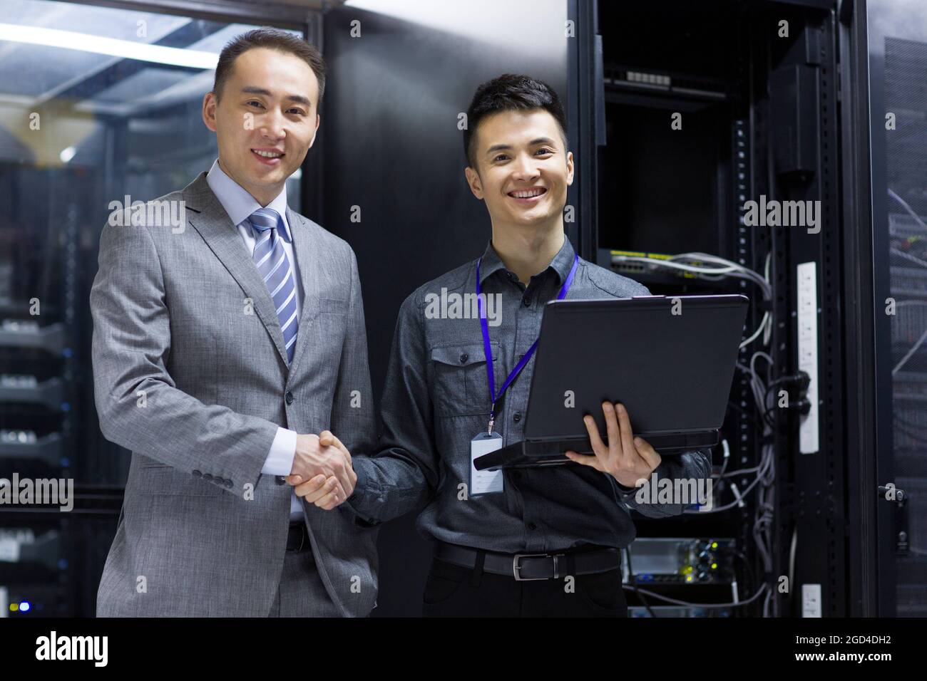 Businessmen shaking hands in computer room Stock Photo - Alamy