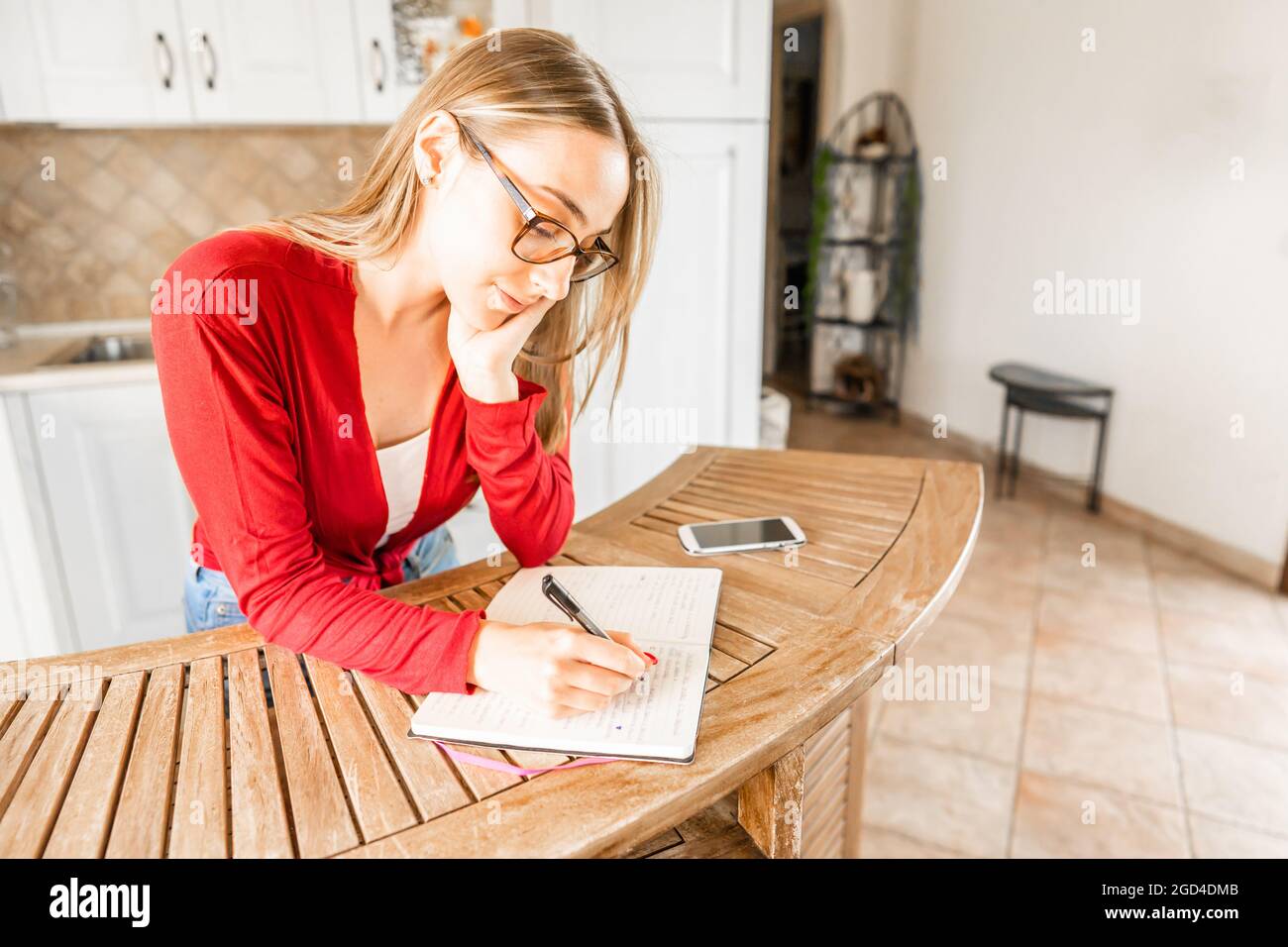 Student girl living alone keeps house bills in kitchen taking notes on ...