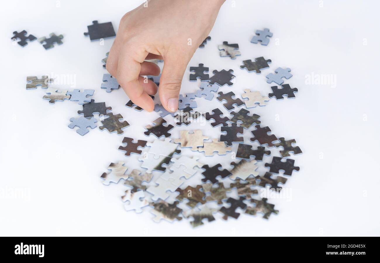 Hand arranging the puzzle pieces on a white surface Stock Photo - Alamy