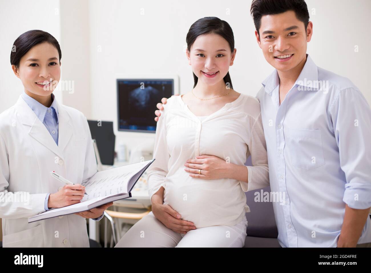 Pregnant woman with husband and doctor Stock Photo - Alamy