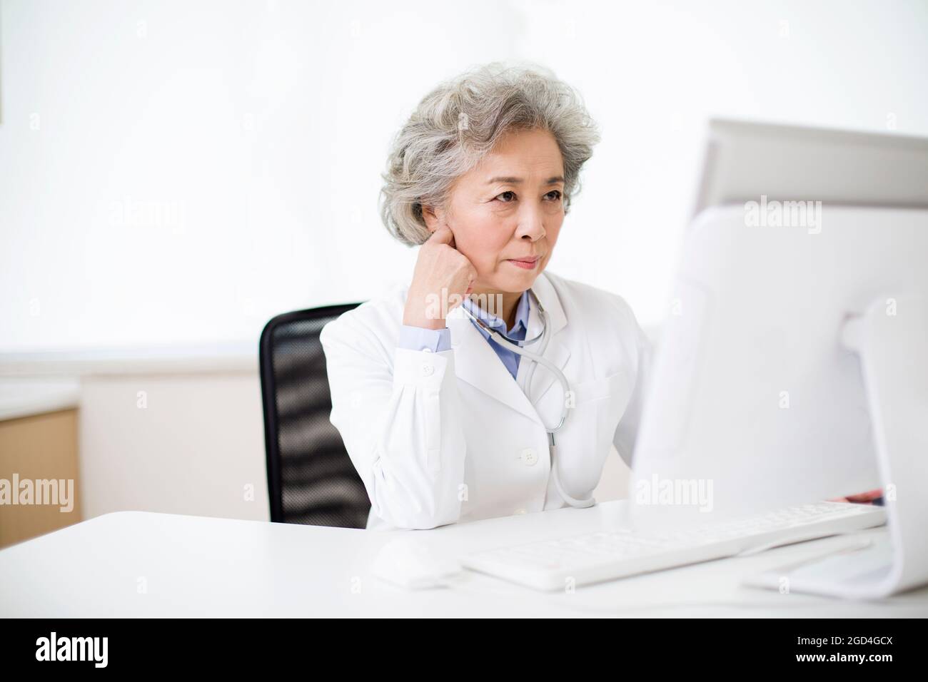 Senior female doctor using computer in office Stock Photo - Alamy