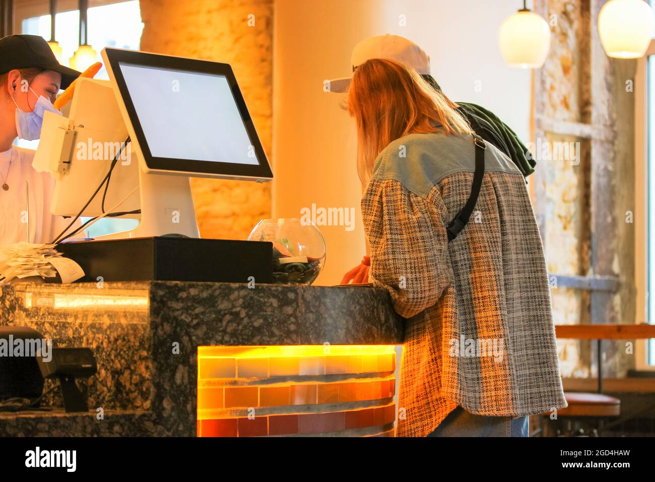 A cashier wearing a medical mask checkout, serves customers at fast ...