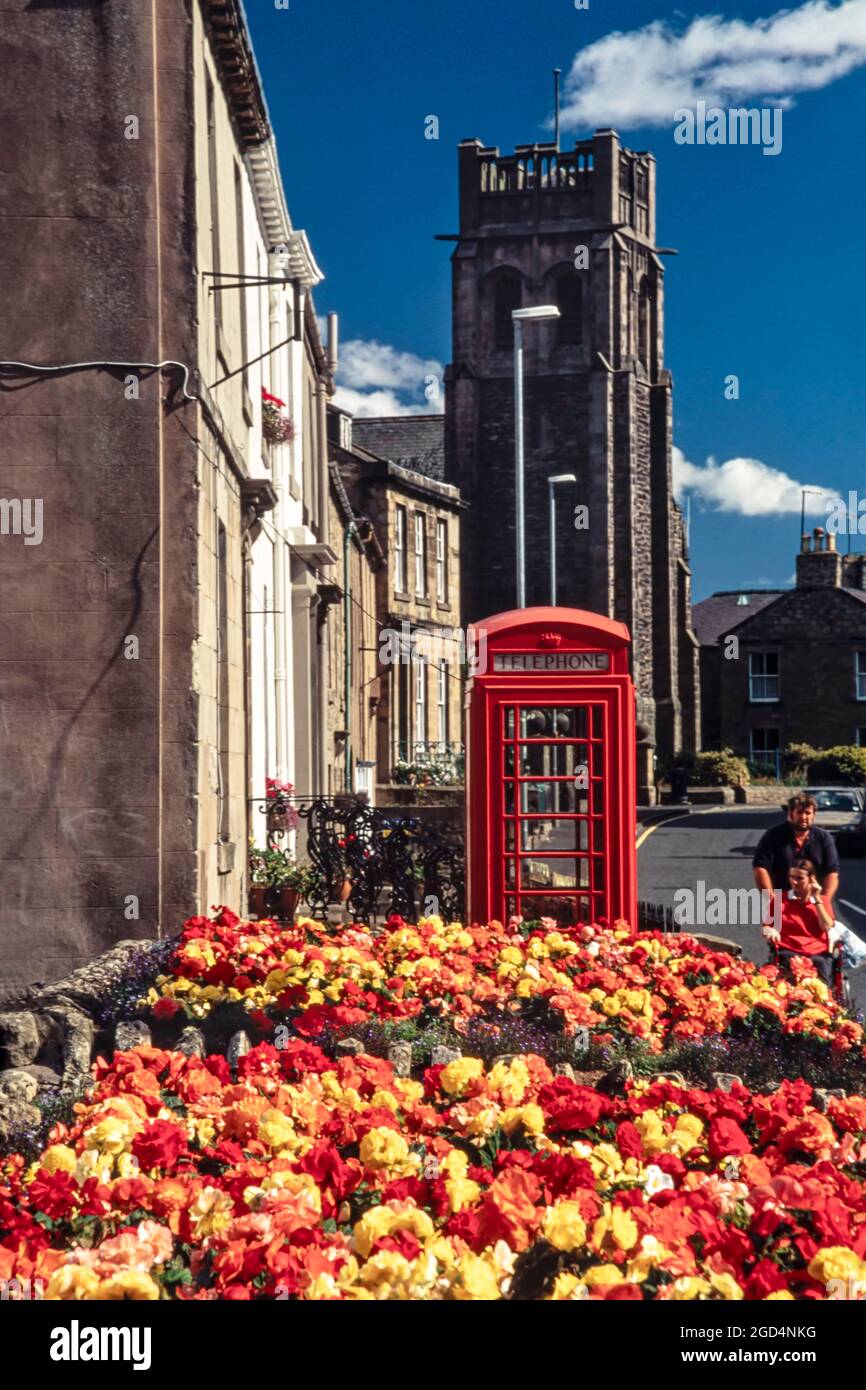 Red telephone box, church tower and floral display in the main street ...
