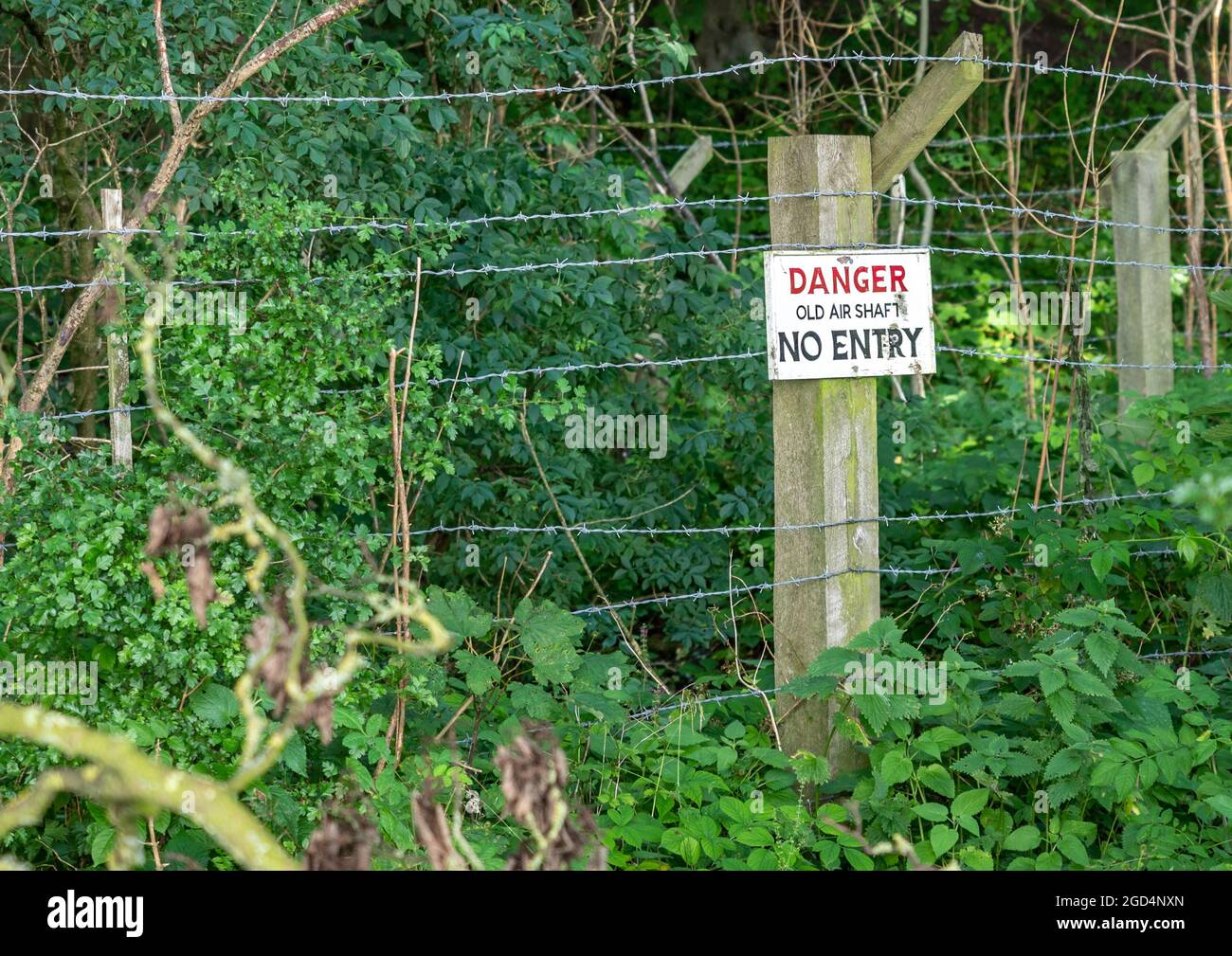 Danger sign for old tunnel air shaft on a wooden fence post with barbed ...