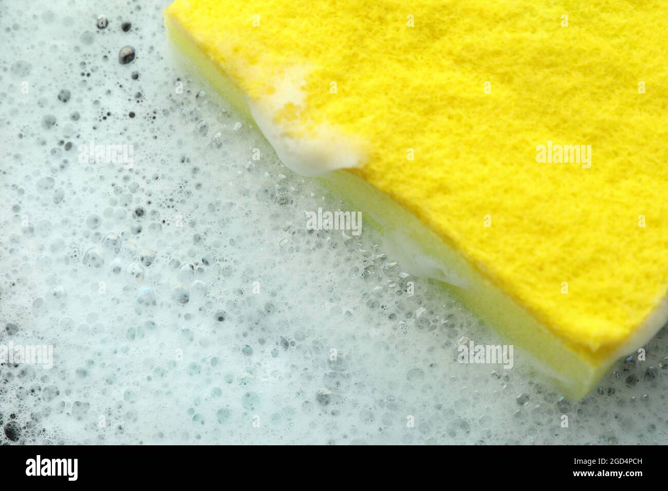 Yellow sponge with detergent foam, close up Stock Photo - Alamy