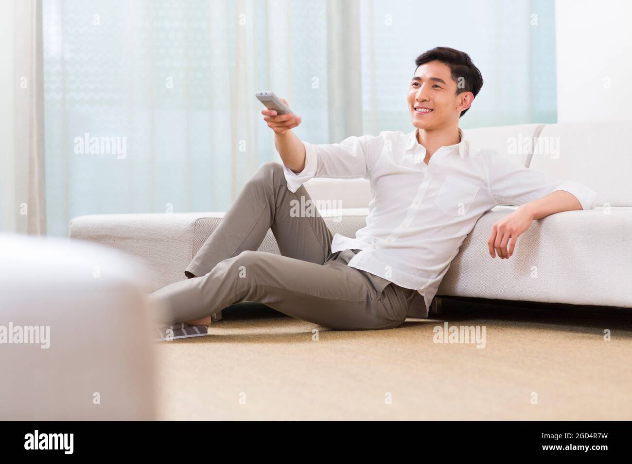 Happy young man watching TV at home Stock Photo - Alamy