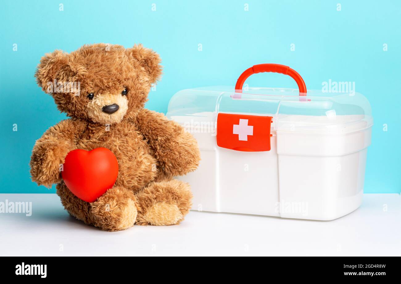 Teddy bear with heart and first aid kit on green background Stock Photo ...
