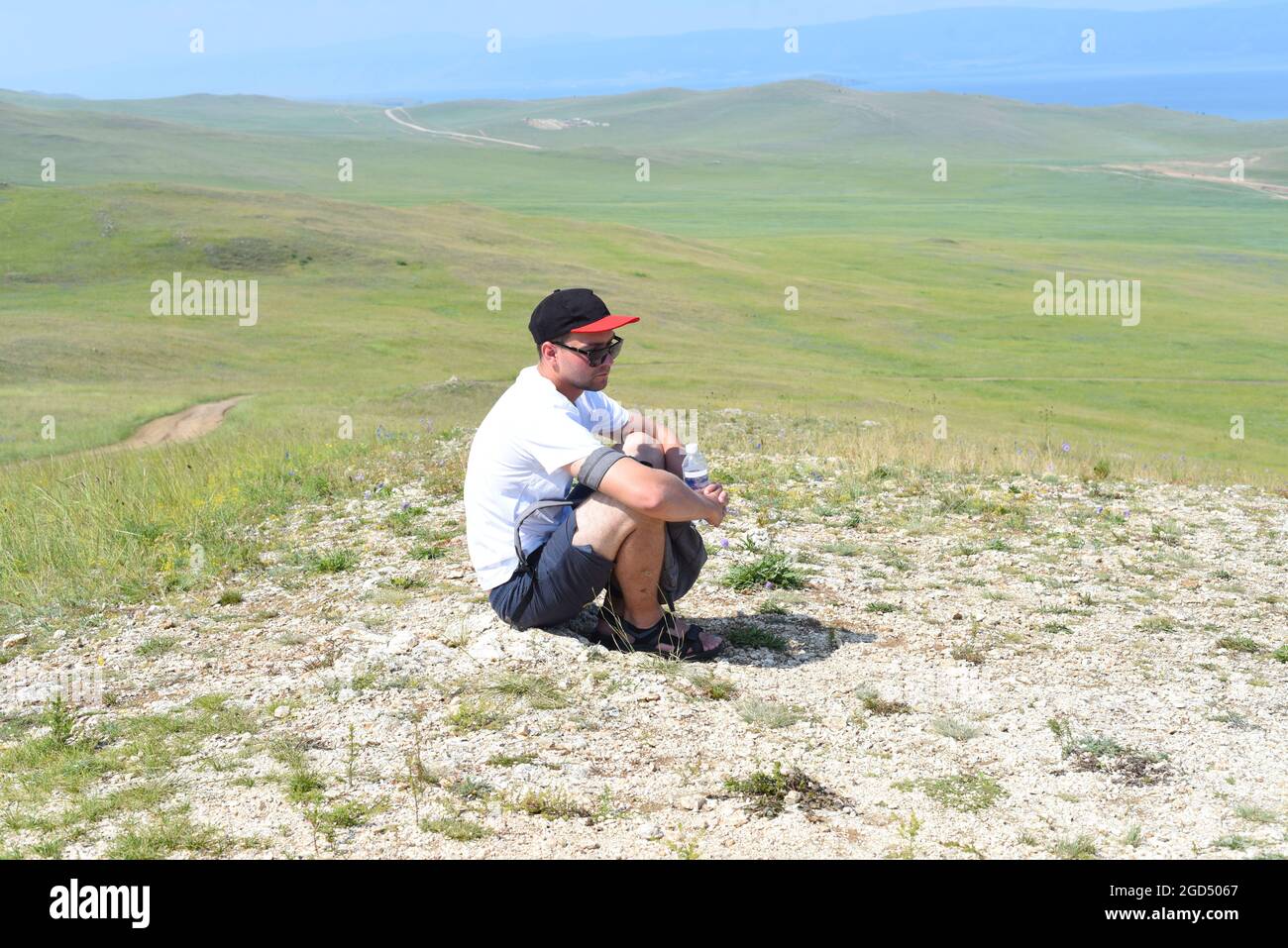 Tired Russian tourist with bottle of water sitting on the ground Stock ...