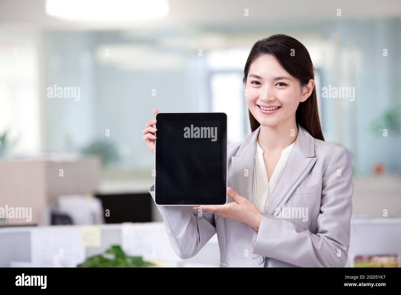 Cheerful office lady showing digital tablet Stock Photo - Alamy