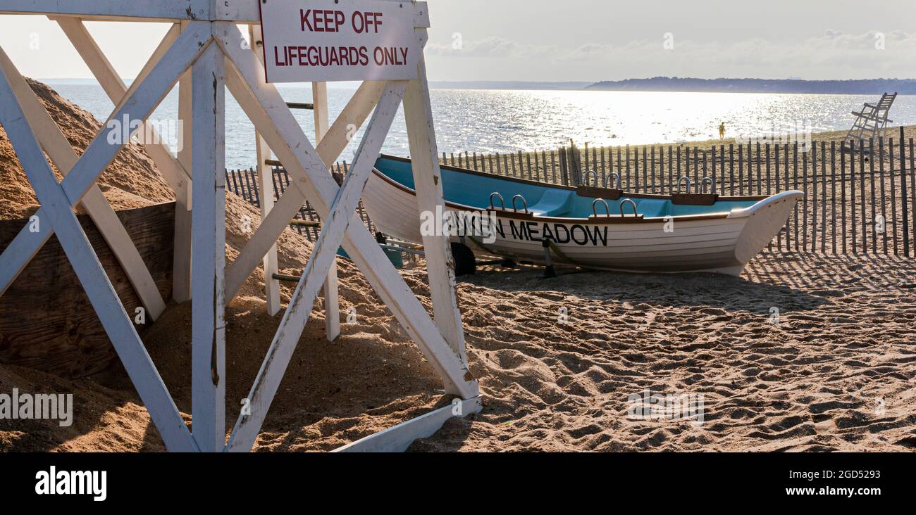 A white lifeguard stand and rowboat on the neach in the early morning ...