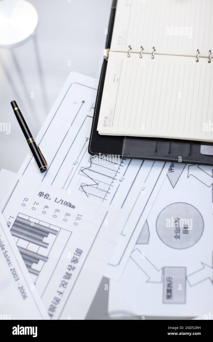 Notepad and business charts on desk Stock Photo - Alamy