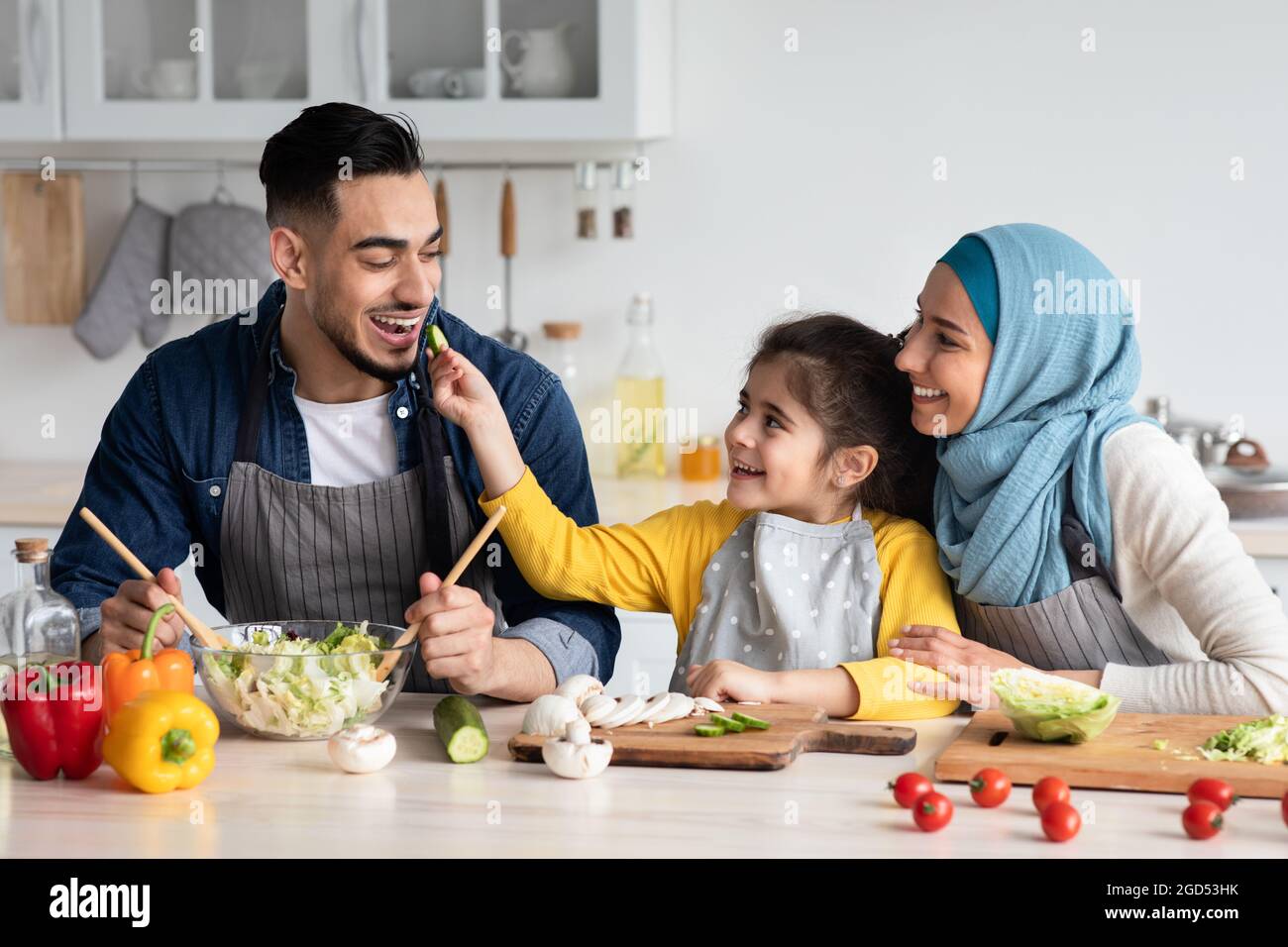 Taste It. Portrait of cute little arab girl feeding her daddy with ...