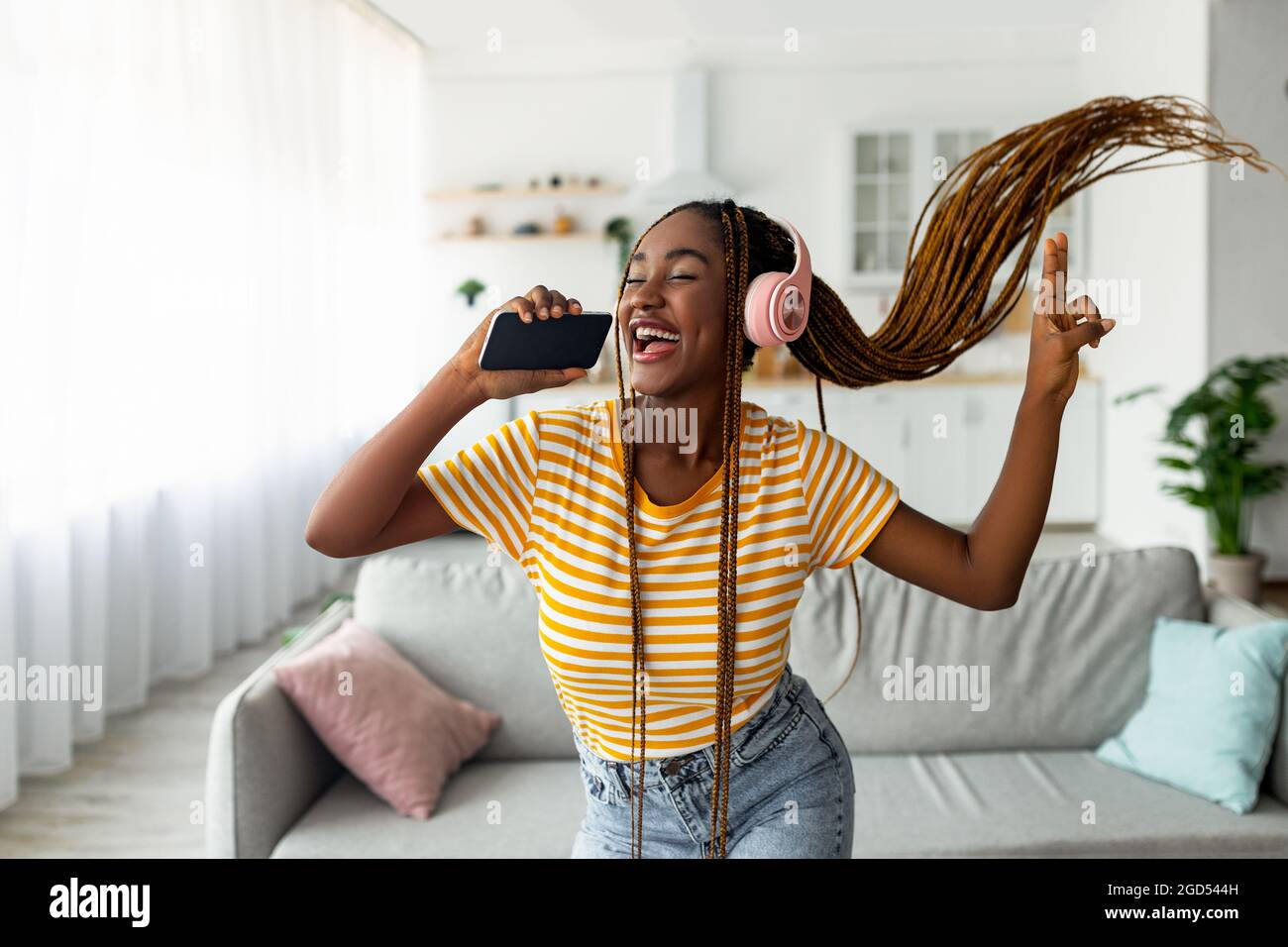 Emotional african american woman listening to music and singing on ...