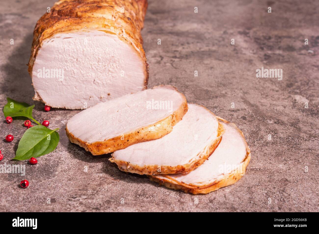 Sliced baked pork loin on a stone concrete background. A trendy hard ...