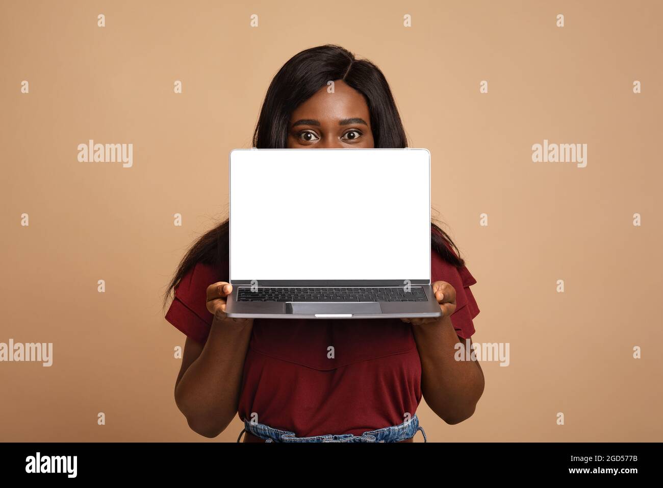 Young black lady holding notebook with empty screen, beige studio ...