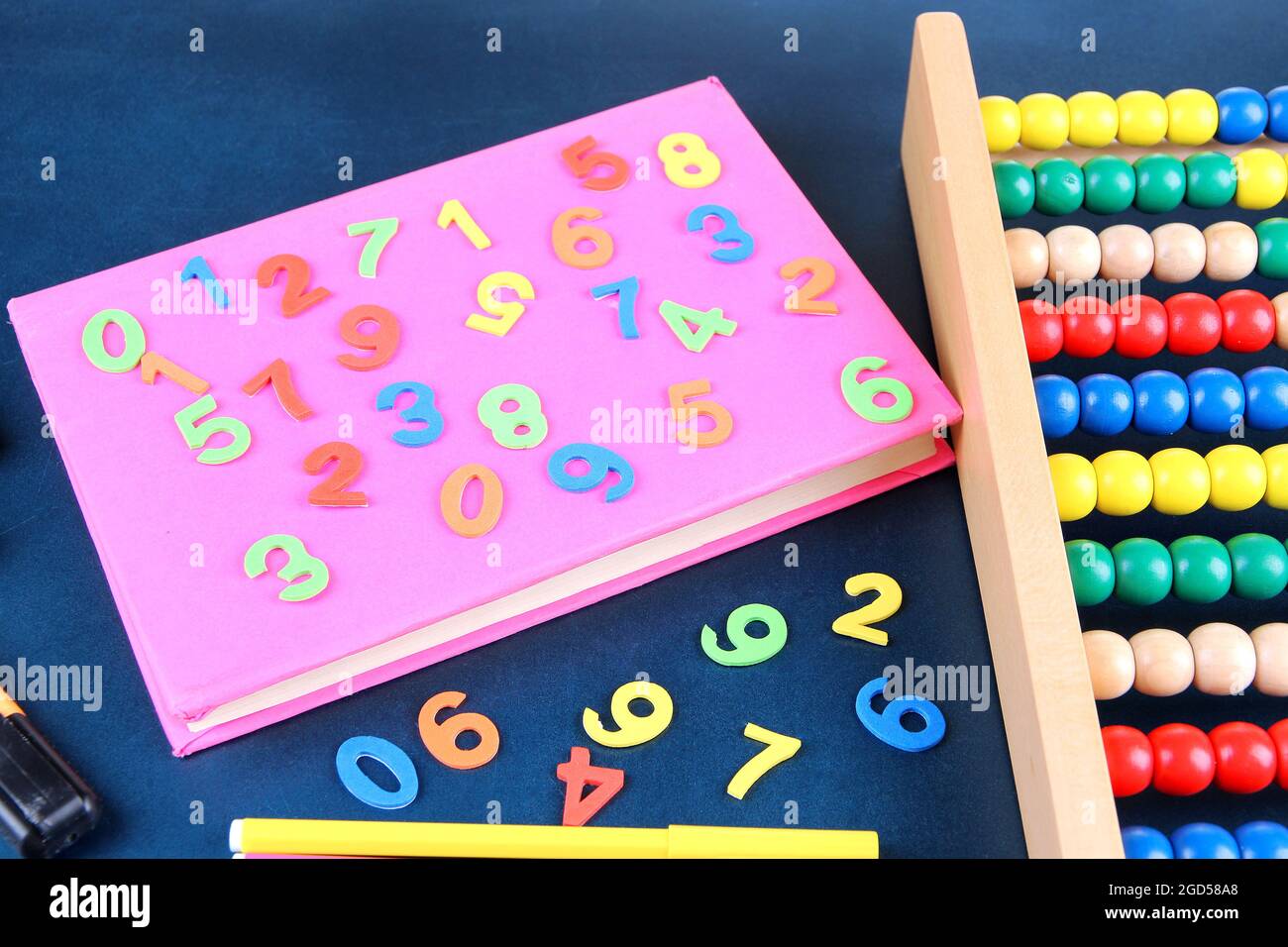 Colorful numbers, abacus, books and markers on school desk background ...