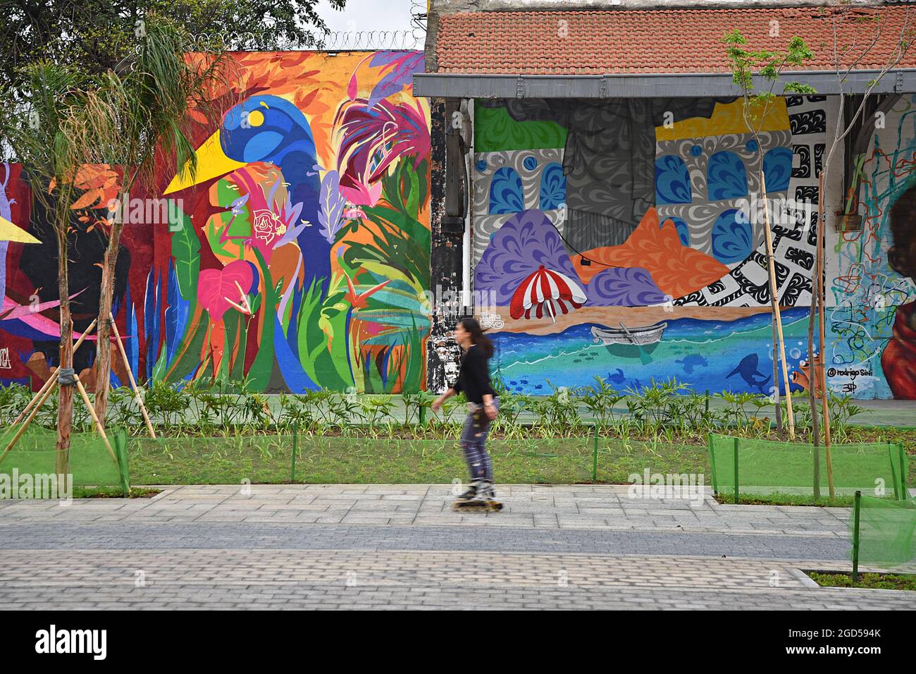 Young girl is roller-skating front of an abandoned building art mural ...