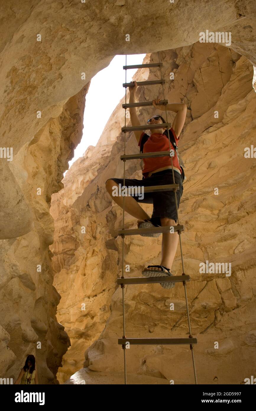 Hiker climbs the rope ladder in a water eroded cave at Barak Stream ...