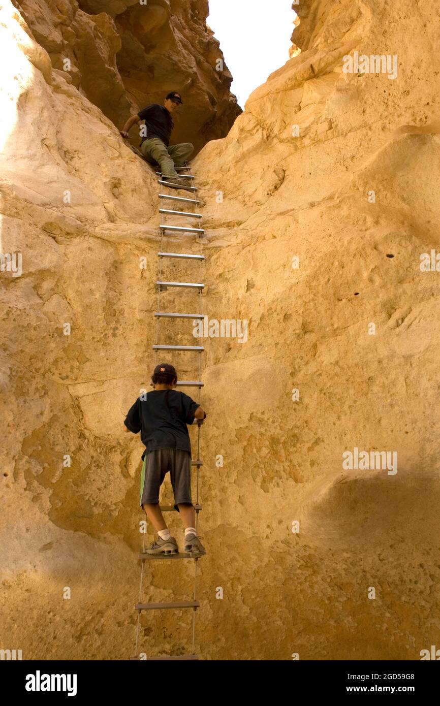 Hiker climbs the rope ladder in a water eroded cave at Barak Stream ...