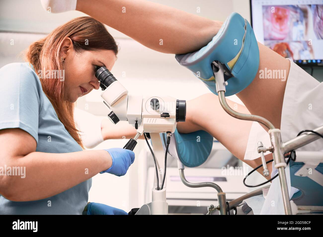 Side view of doctor using colposcope while examining woman patient ...