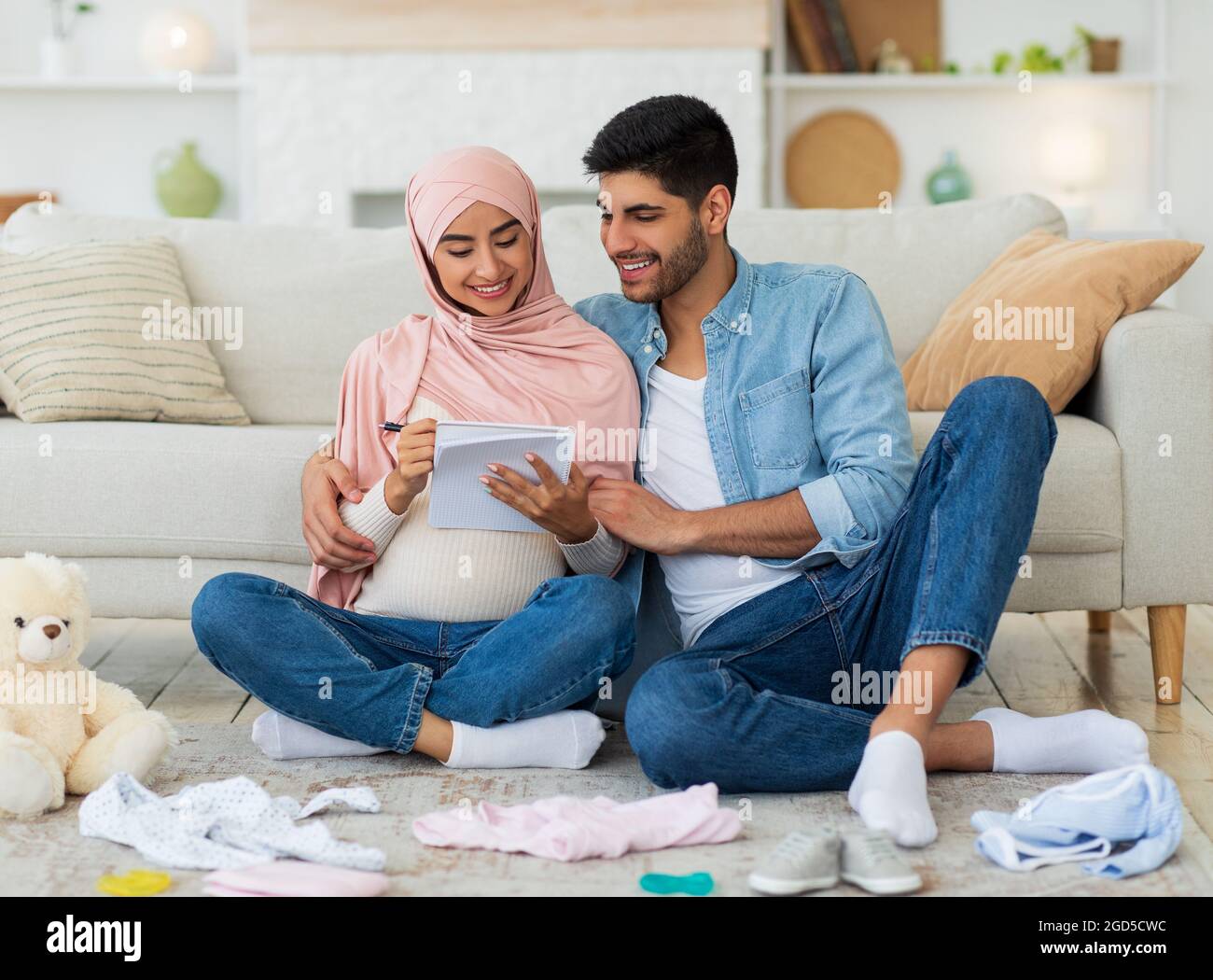 Preparing for childbirth. Pregnant muslim couple making checklist of ...